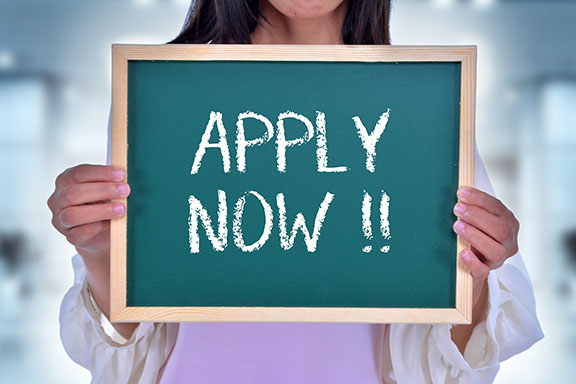 Young Women holding chalkboard with text Apply Now | Pathway Homes